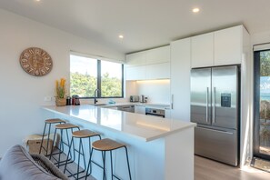 Uma cozinha moderna com uma ilha central, eletrodomésticos de aço inoxidável e uma janela ampla.