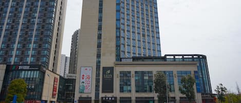 Um hotel com uma placa vertical chamativa, várias janelas e uma fachada moderna.