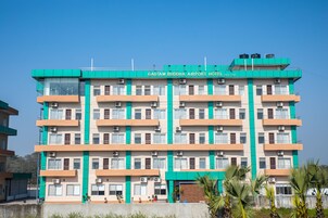 Um edifício de vários andares com uma placa indicando "GAUTAM BUDDHA AIRPORT HOTEL PVT LTD". Apresenta um design moderno com telhado plano e várias varandas.