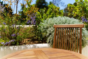 Uma cadeira e mesa de madeira num jardim com várias plantas e flores.