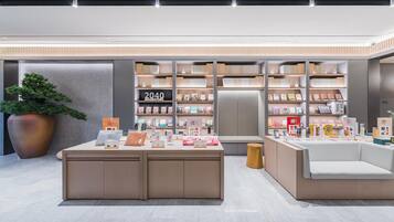 Uma livraria moderna com uma mesa de exposição central, estantes com livros e uma grande planta em vaso.