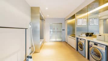 Quarto de hotel moderno com um corredor que leva a uma porta, um aspirador de pó e uma máquina de lavar.