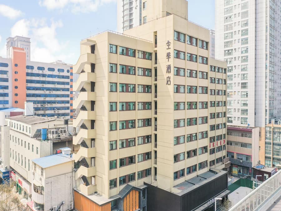 Um hotel com vários andares e design moderno, com uma entrada imponente e um terraço no telhado.