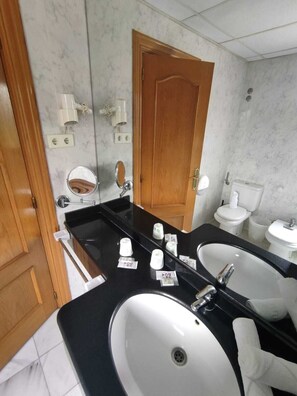 Casa de banho com duas pias, um espelho e uma porta de madeira.