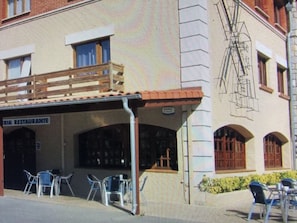 Um edifício com uma placa indicando "Ria Restaurante" e área externa com mesas e cadeiras.
