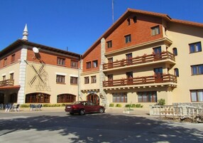 Um hotel com vários andares, de estilo arquitetônico tradicional, com varandas e uma escultura proeminente de moinho de vento na fachada.