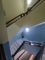 Uma escada com corrimãos de madeira e um aparelho de iluminação na parede.