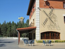 Um hotel com área de estar coberta ao ar livre e um grande desenho arquitetônico na fachada do edifício.