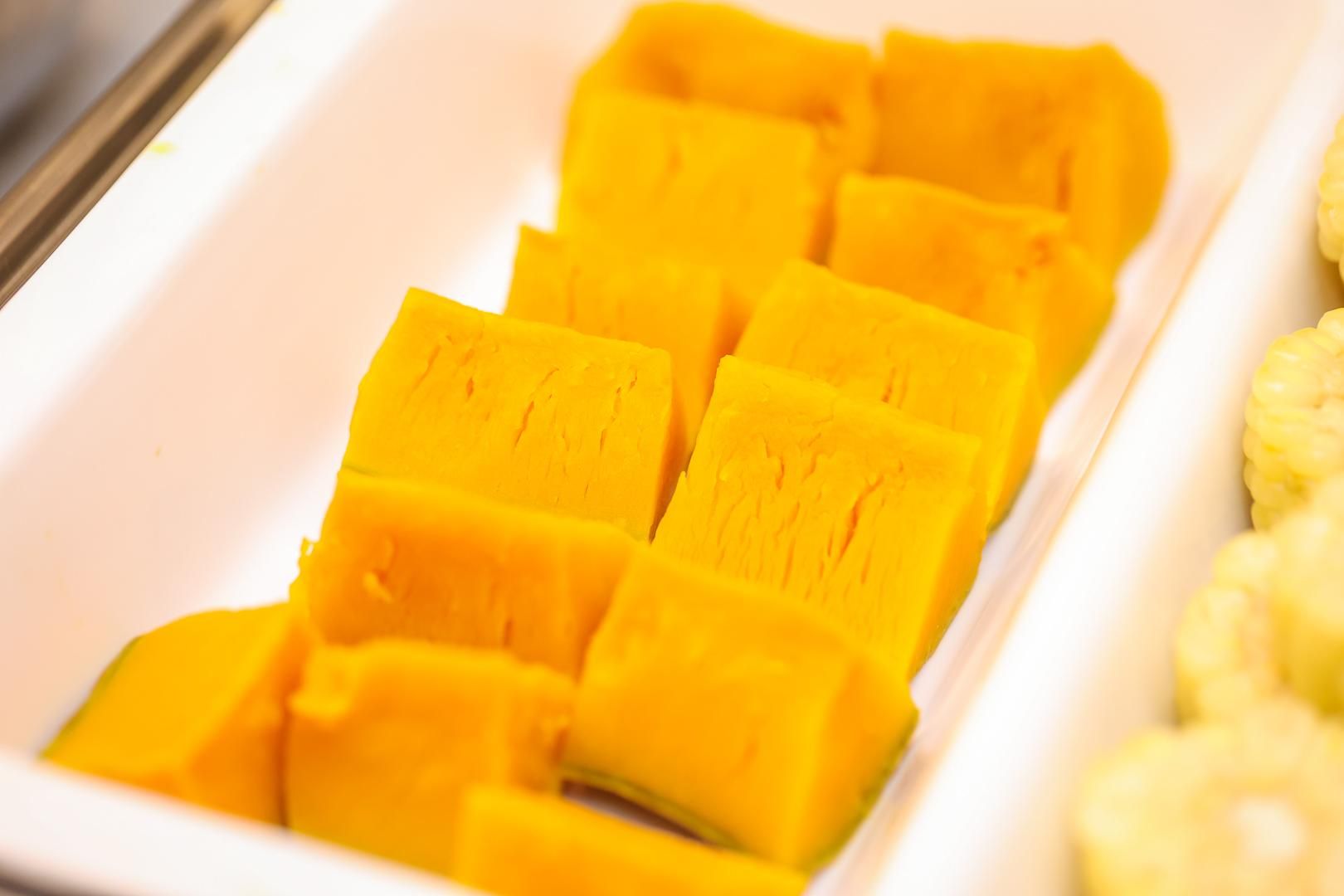 Uma tigela branca e retangular com várias fatias de fruta amarela, provavelmente manga, dispostas de forma organizada.