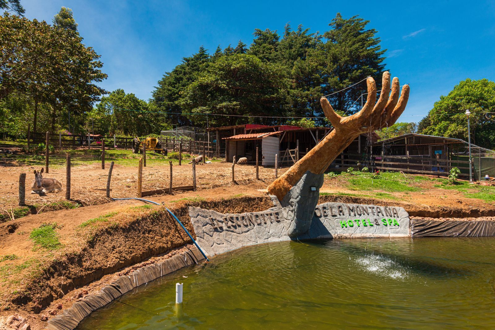 Escultura grande de uma mão em um espelho d'água, com uma placa que diz "Hotel & Spa".