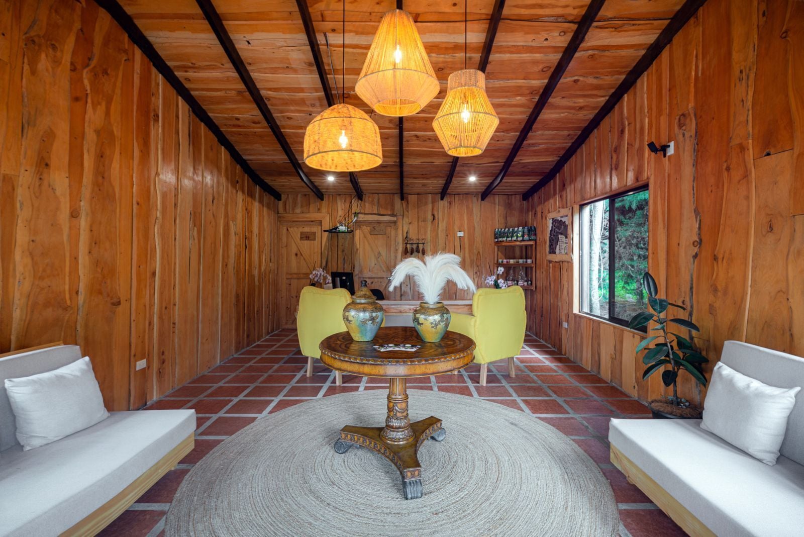 Um interior de madeira com uma mesa redonda, duas cadeiras amarelas e um sofá branco.