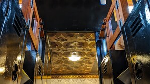 Interior de elevador imponente e ricamente decorado, com teto espelhado e parede de espelhos.