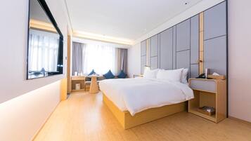 Quarto de hotel moderno com uma cama grande, uma escrivaninha e uma área de estar.
