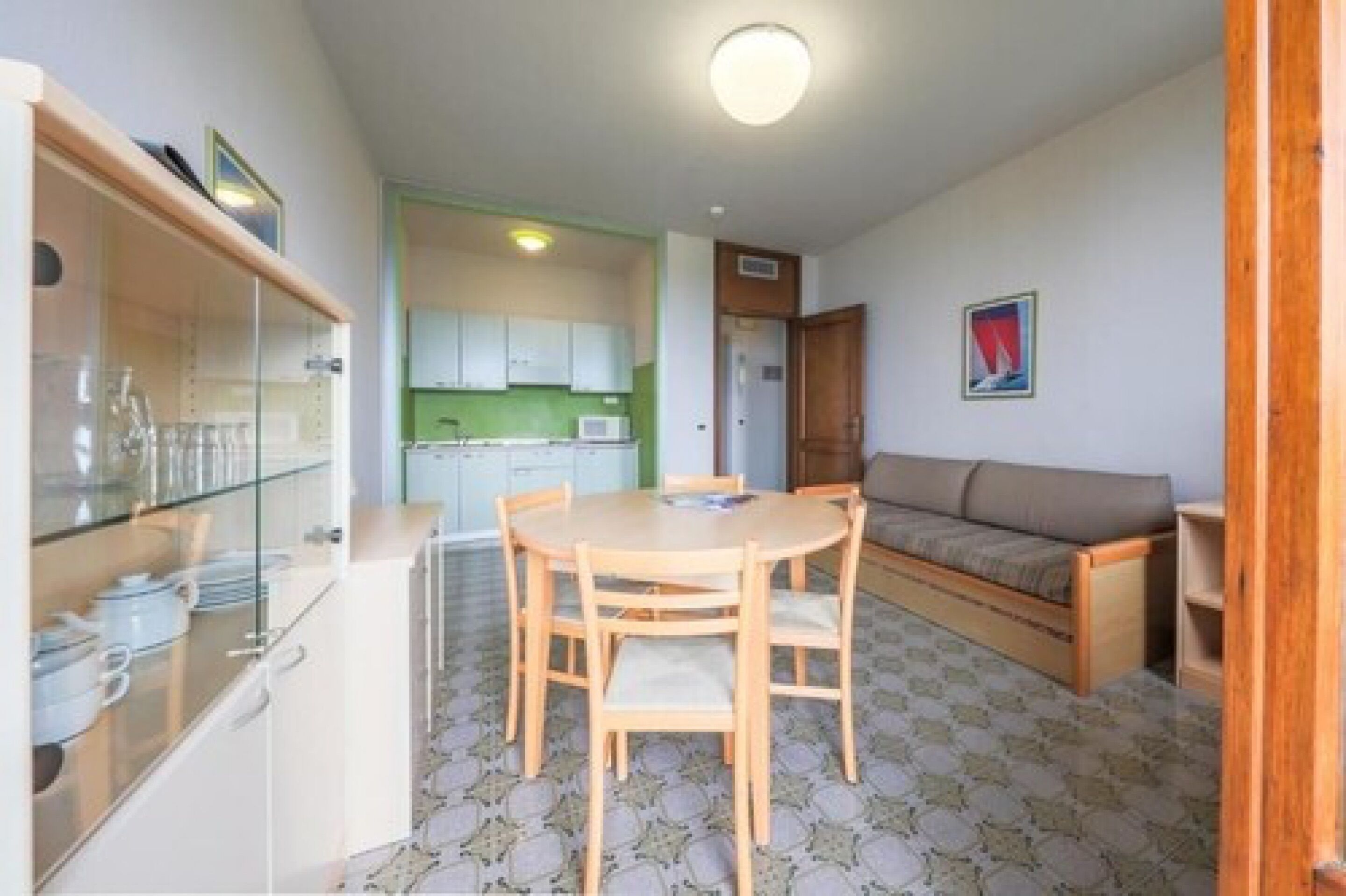 Um espaço compacto com cozinha compacta, área de jantar com mesa e cadeiras, e um sofá.
