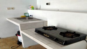 Uma cozinha compacta com fogão a gás, pia e um balcão pequeno.