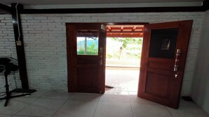 Um quarto com parede de tijolos brancos, porta de madeira e um ventilador.