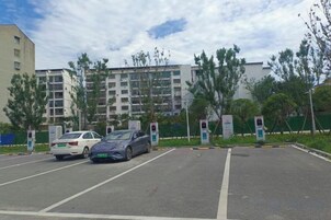 Estacionamento com carros e um edifício ao fundo.