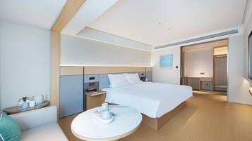 Quarto de hotel moderno com uma cama grande, mesas de cabeceira, uma mesa de centro redonda e um closet espaçoso.
