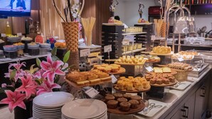 Buffet com diversos alimentos e uma tela de televisão ao fundo.