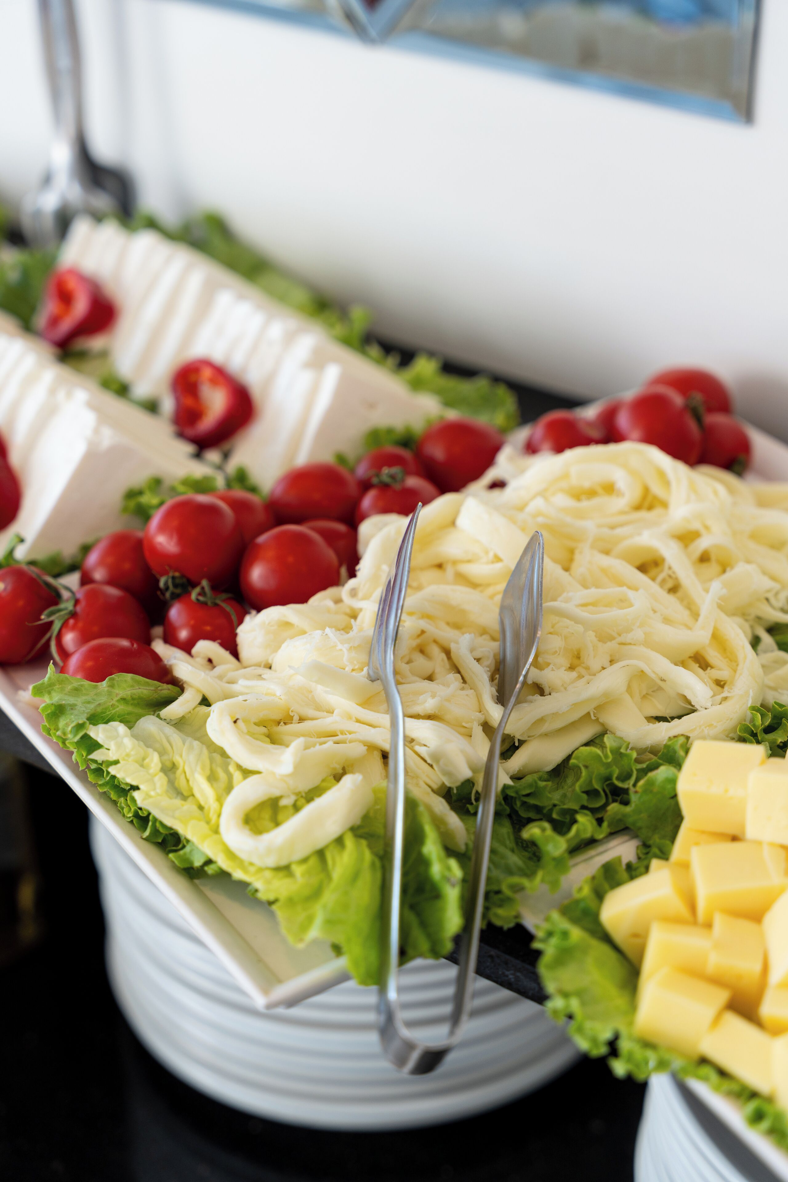 Uma mesa de buffet com massa, queijo e tomate cereja.