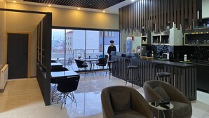 Uma área de bar moderna com teto alto e vista para a cidade.