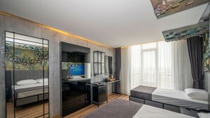 Quarto de hotel moderno com uma cama, uma escrivaninha e um espaço de estar.