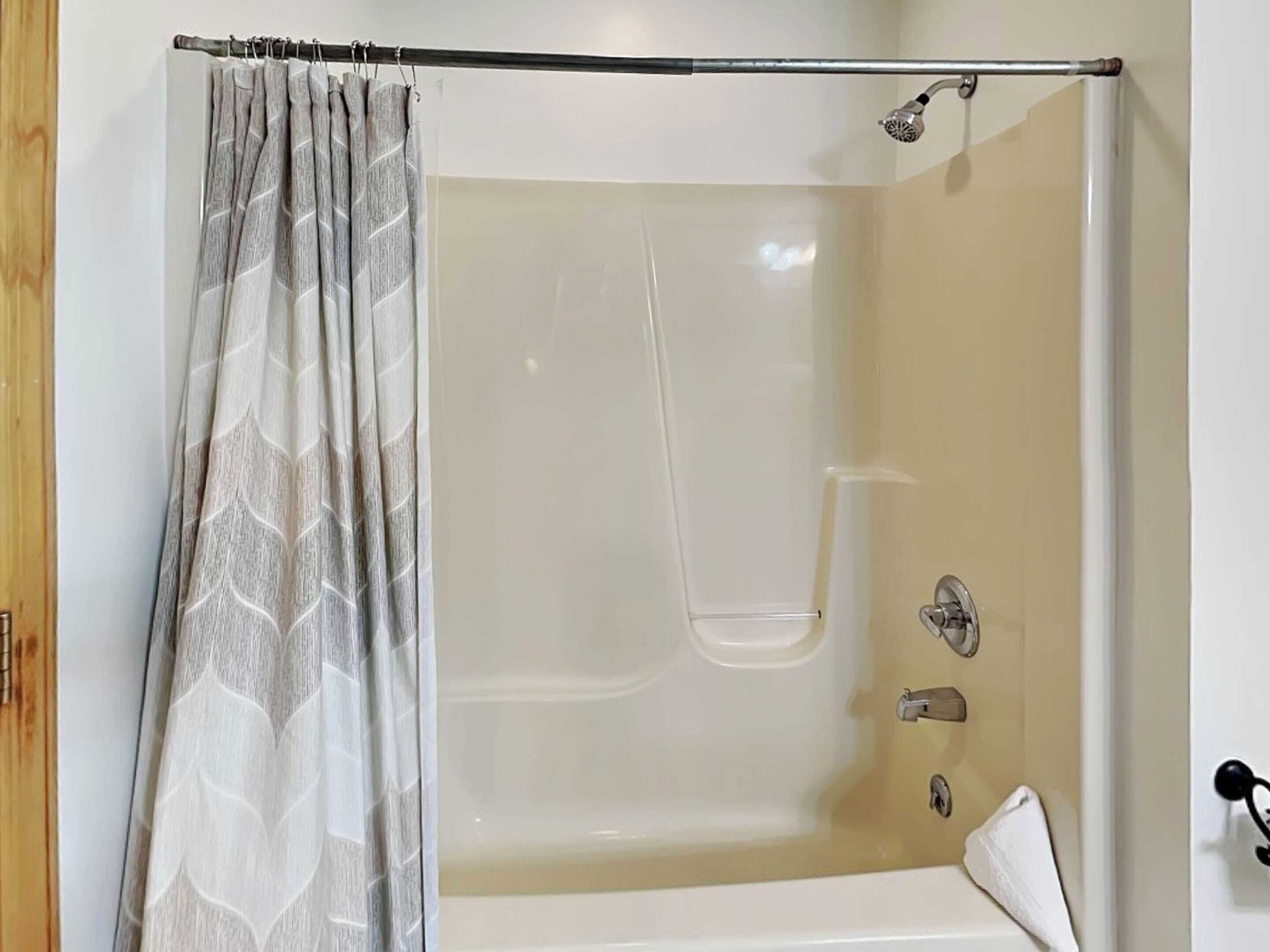 Um banheiro moderno com chuveiro em box de vidro, chuveiro manual e porta-toalhas.