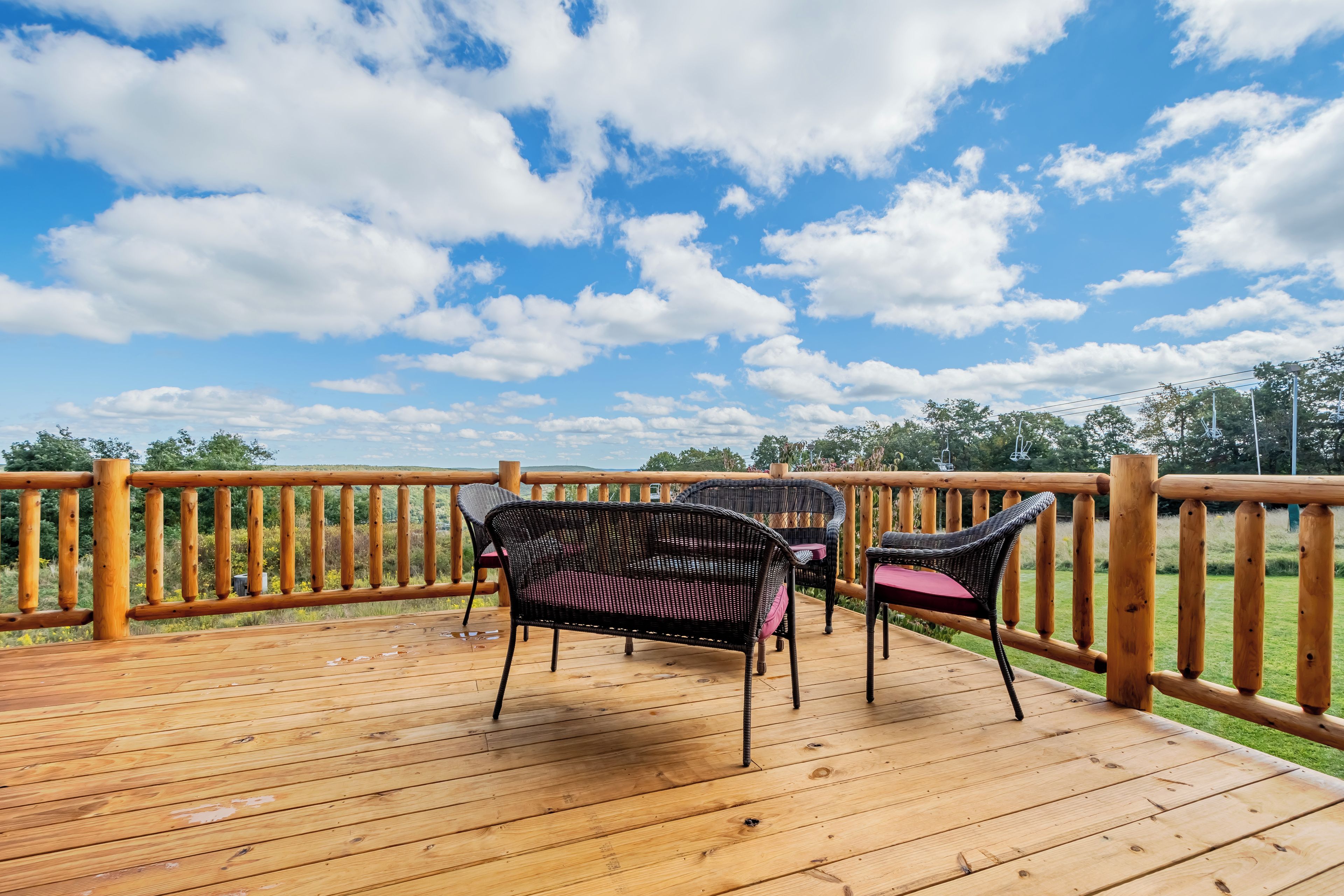 Um deck de madeira com móveis de vime e vista para o céu.