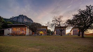 Um edifício com vários quartos, um espaço amplo e uma montanha ao fundo.