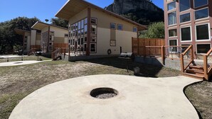 Um edifício moderno com grandes janelas e telhado plano, rodeado por área ajardinada e árvores.