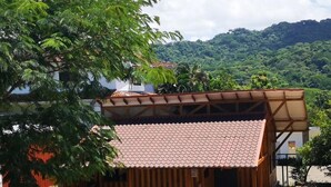 Um edifício de madeira com telhado de cerâmica, rodeado por vegetação e colinas.