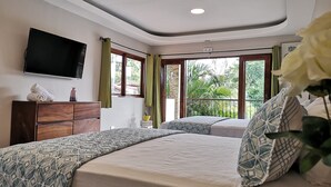 Quarto com cama, televisão na parede e janela com cortinas.