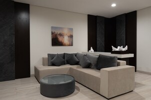 Uma sala de estar moderna com um sofá seccional, uma mesa de centro de vidro e um quadro na parede.
