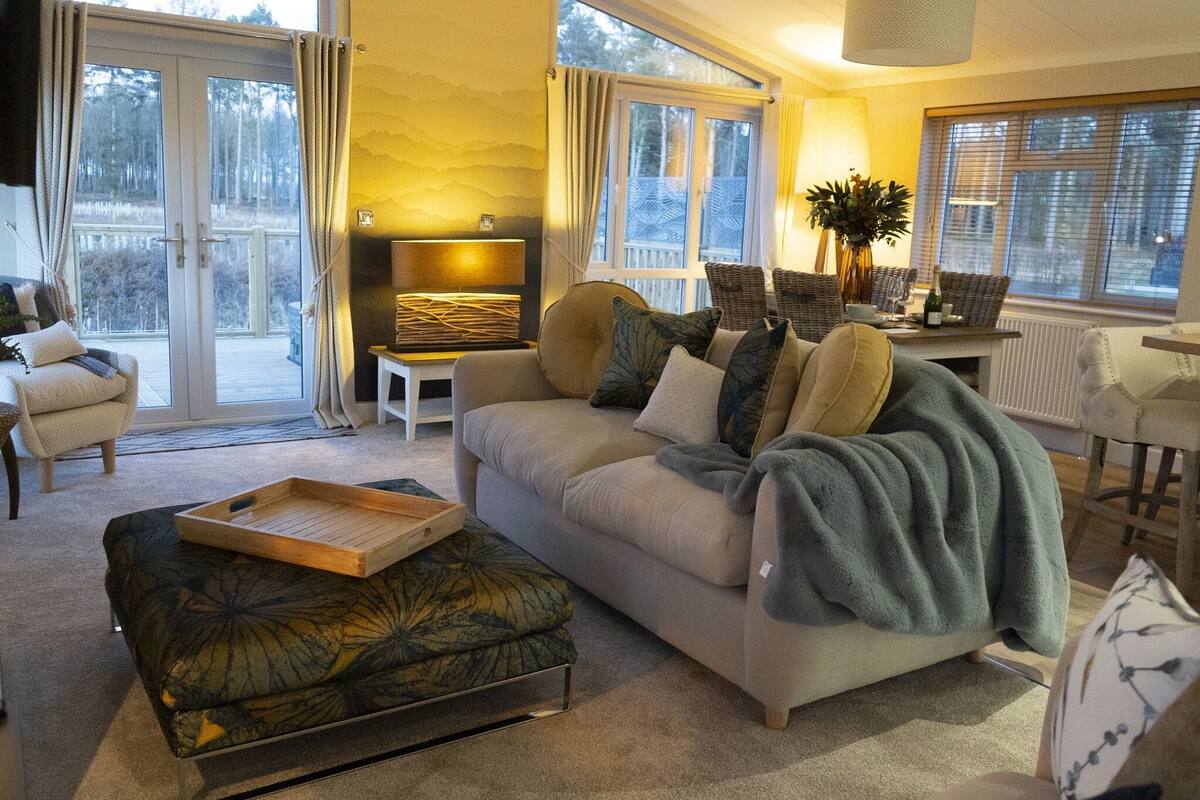 Uma sala de estar aconchegante com sofá, banquinho e uma mesa de jantar.