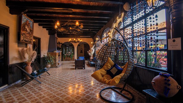 Um interior acolhedor com uma cadeira suspensa, vigas de madeira e um detalhe decorativo na parede.