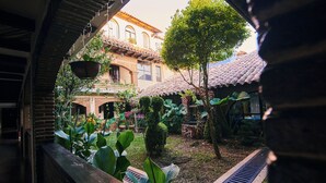 Um pátio com um edifício de tijolos, uma árvore e diversas plantas.