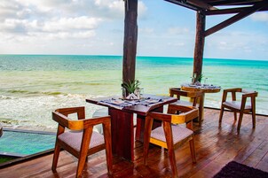 Um deck de madeira com mesa e cadeiras, com vista para águas oceânicas turquesa.
