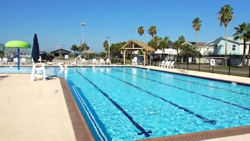 Piscina com água azul cristalina, rodeada por espreguiçadeiras e um gazebo.