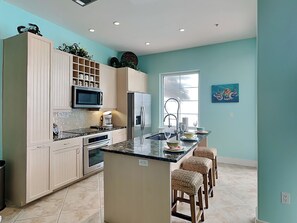 Uma cozinha com ilha central, eletrodomésticos embutidos e janela que oferece luz natural.