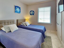 Quarto com duas camas, janela com persianas e uma obra de arte na parede.