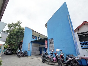 Um edifício com fachada azul, entrada protegida por portão e várias motocicletas estacionadas.