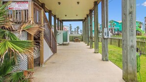 Uma galeria coberta com pilares de madeira, um pequeno depósito e uma mesa para piquenique.