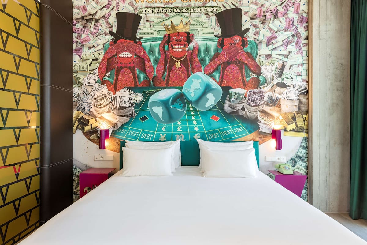 Quarto com cama, roleta e parede decorada com dinheiro e figuras caricaturais.