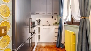 Uma cozinha compacta com armários cinza, um micro-ondas, uma pia e um radiador amarelo.