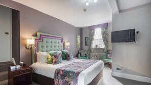 Quarto com cama grande, mesa de cabeceira, cômoda, televisão e janela com cortinas.