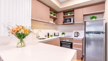 Uma cozinha moderna com ilha central, eletrodomésticos de aço inoxidável e prateleiras embutidas com plantas em vasos.