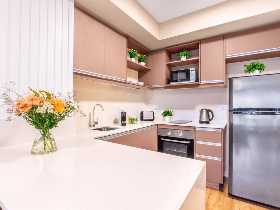 Uma cozinha moderna com ilha central, eletrodomésticos de aço inoxidável e prateleiras embutidas com plantas em vasos.