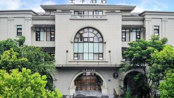 Um hotel com estilo arquitetônico tradicional, destacando uma entrada em arco e uma grande janela com padrão de grade.