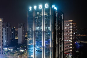 Um hotel moderno e alto, com linhas verticais iluminadas e sinalização.
