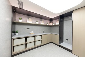 Uma casa de banho moderna com teto curvo, prateleiras embutidas com plantas, uma pia e cestos de arrumação.